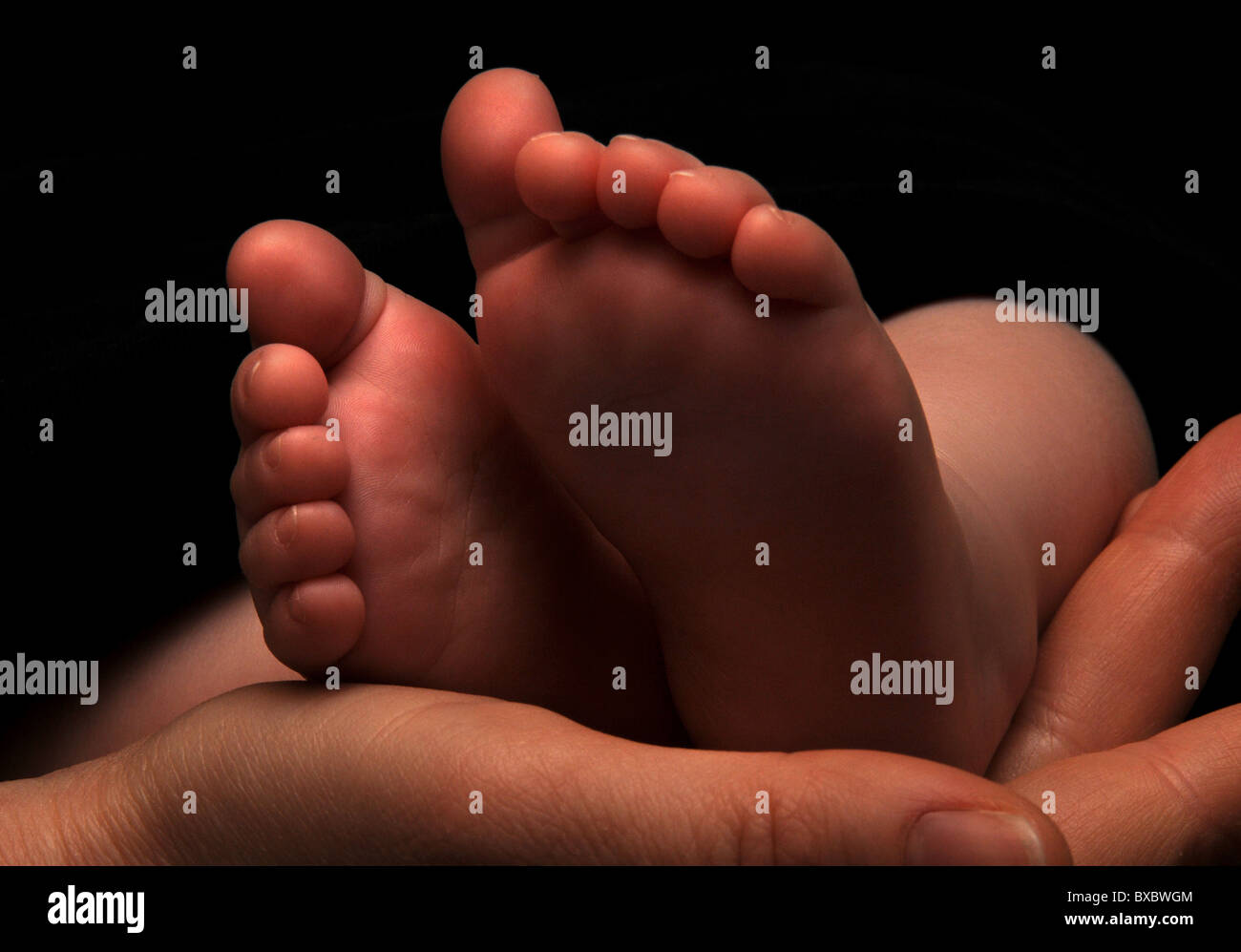The feet of a 4-month-old child are cradled in the hands of their ...