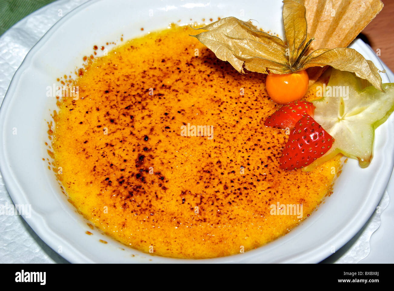 Warm creme brulee with strawberry gooseberry star fruit slice garnish ...