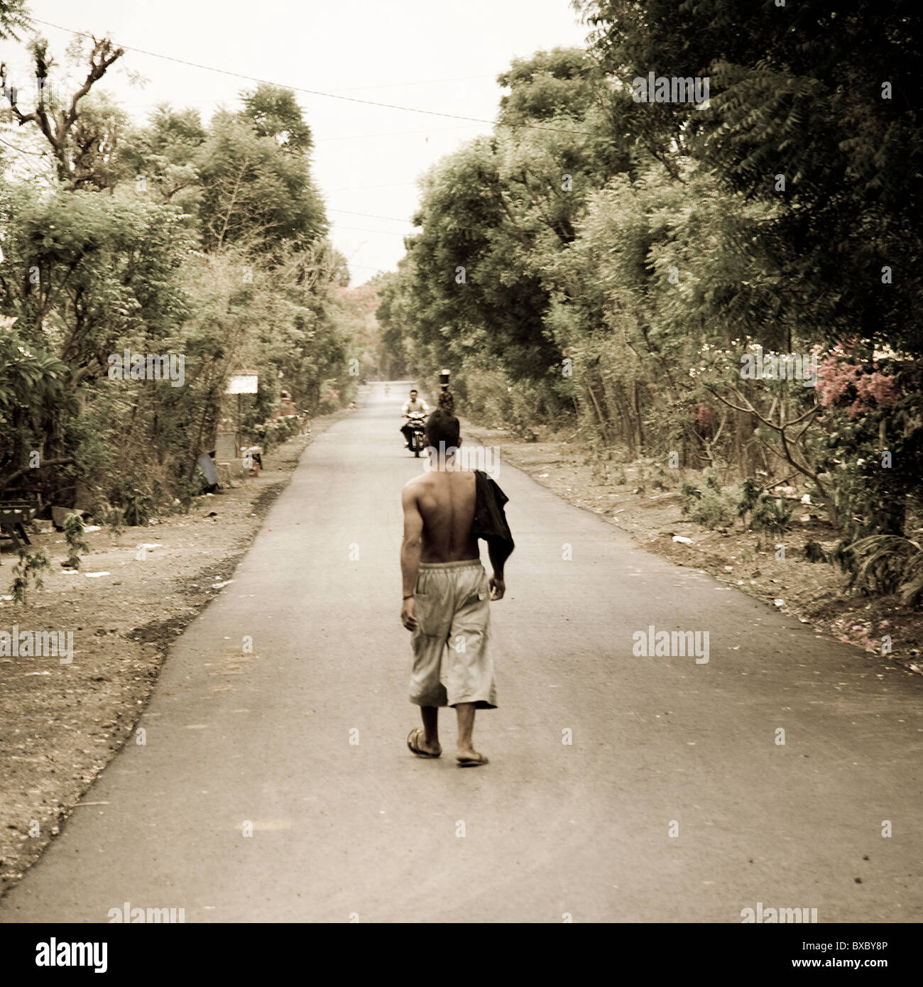 Back view of a man walking on roadway in Bali Stock Photo - Alamy