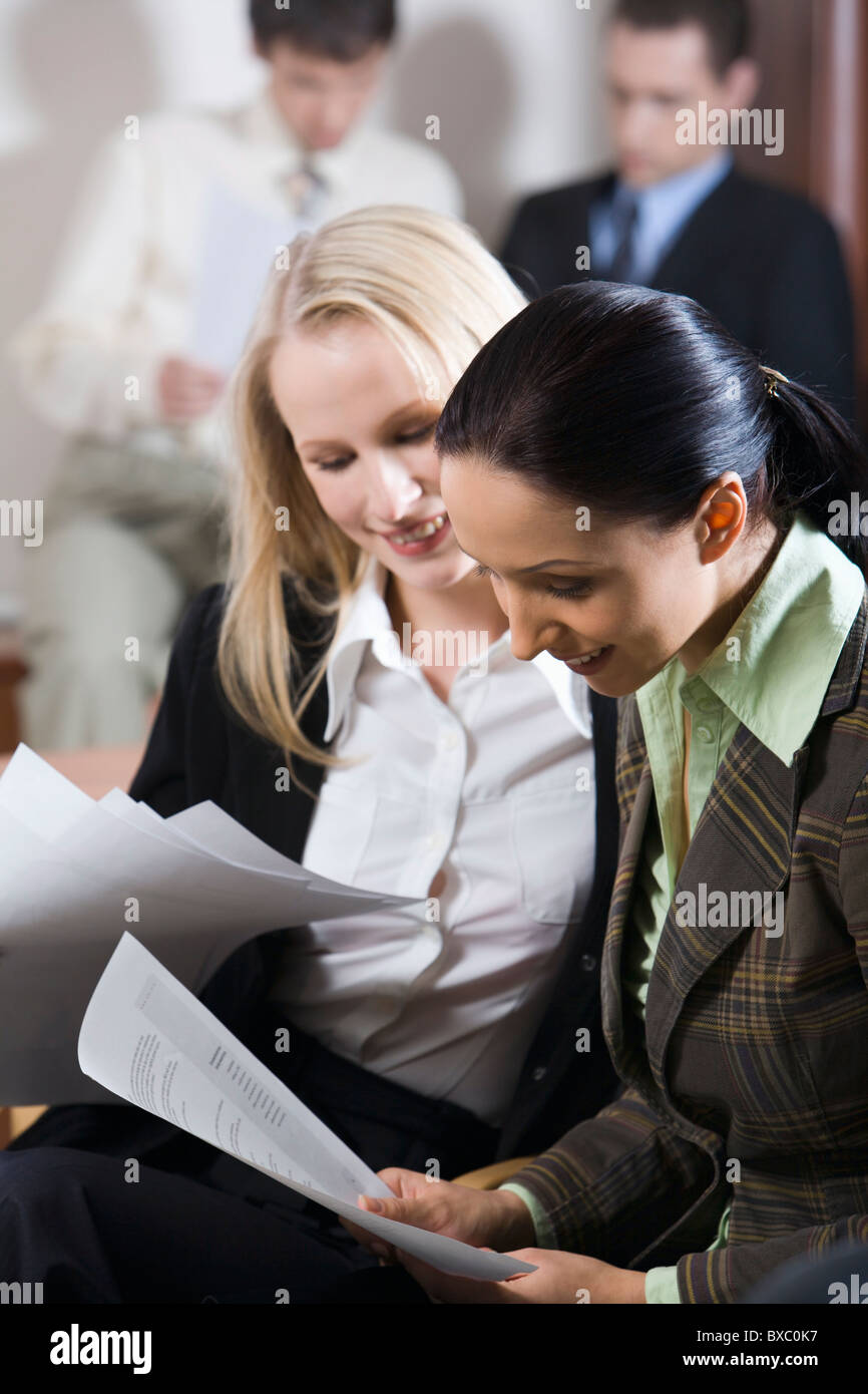 Two pretty women reading notes and two reading men on the background ...