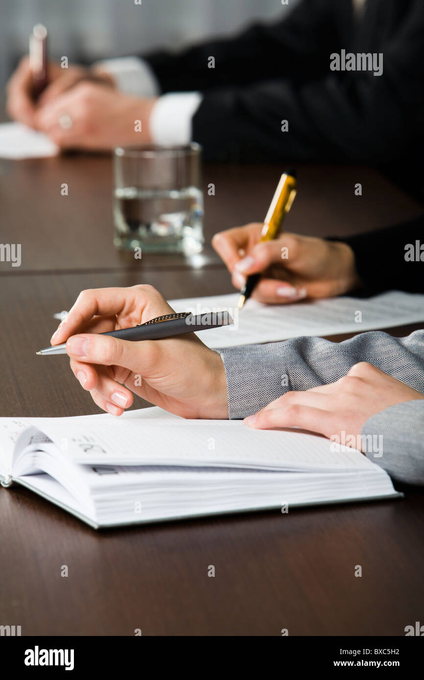 Row of writing hands holding pens, notebooks and glass of water Stock ...