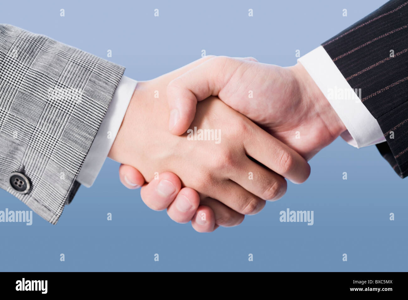 Close-up of shaking hands making an agreement on the blue background ...