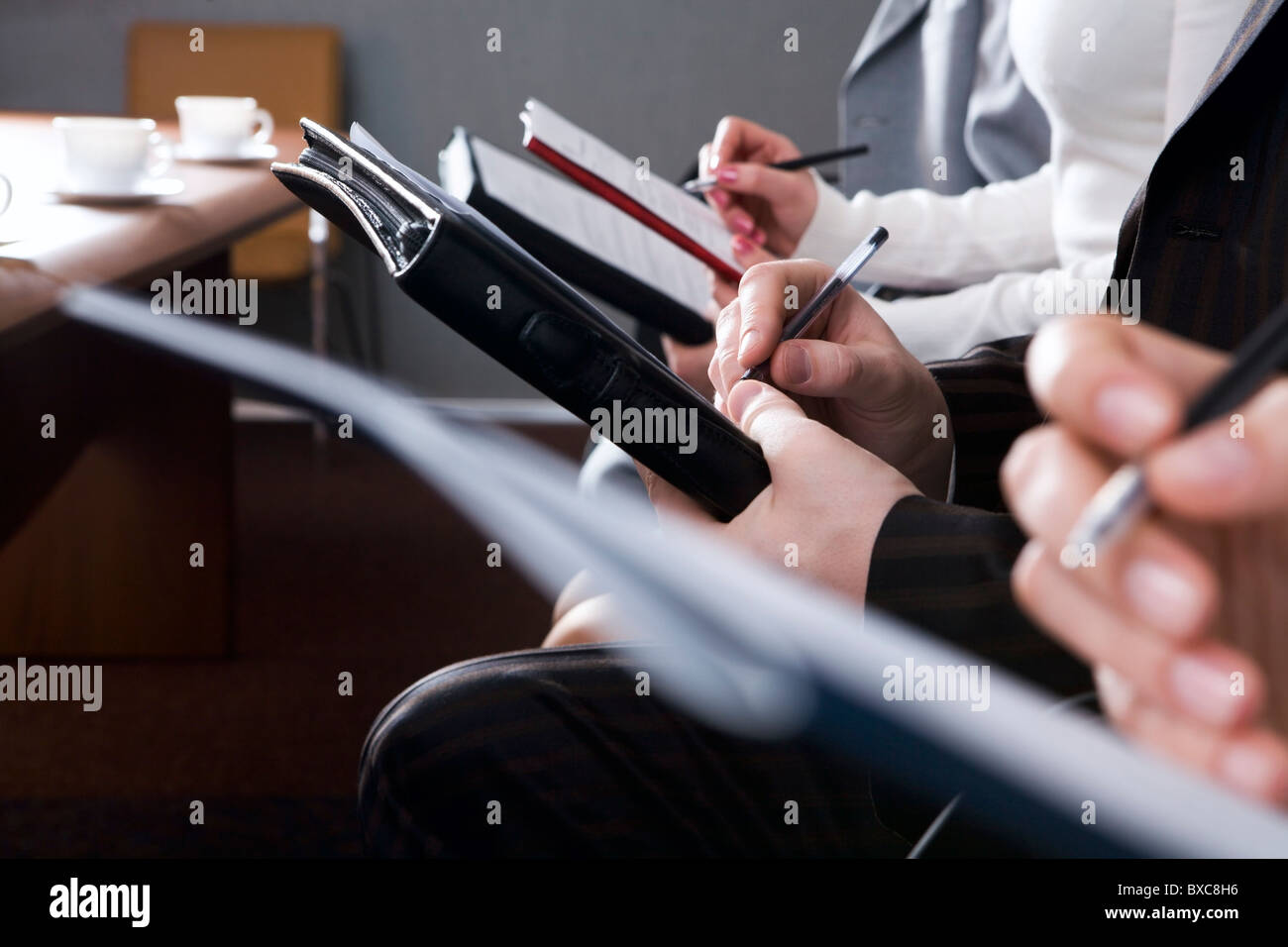 Row of hands filling in a form Stock Photo - Alamy