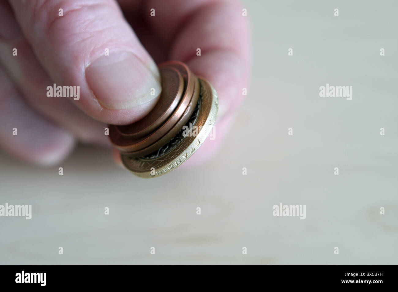 Some sterling coins held between and index finger and thumb Stock Photo ...