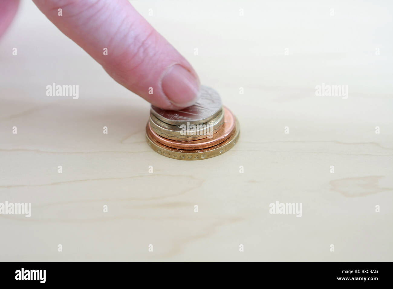An index finger pointing at a stack of mixed sterling coins Stock Photo ...