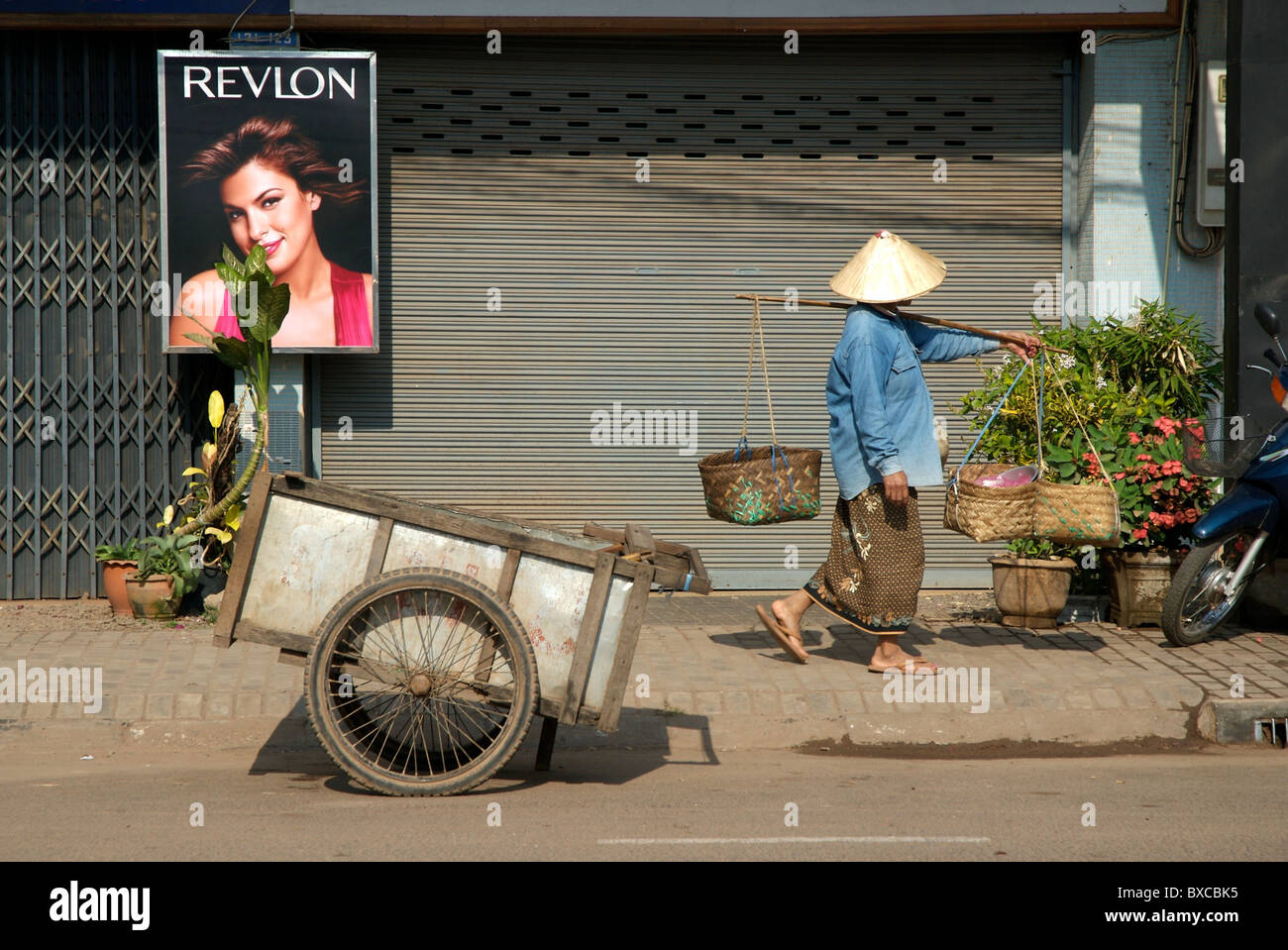 Old Lao woman is standing next to a modern advertising poster Stock ...