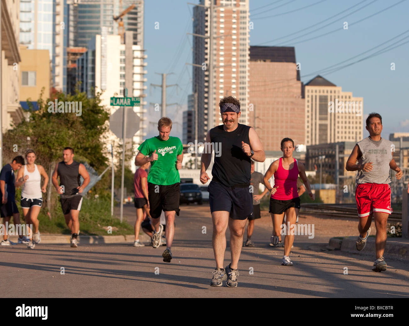 Men and women jog across street during exercise class in downtown ...