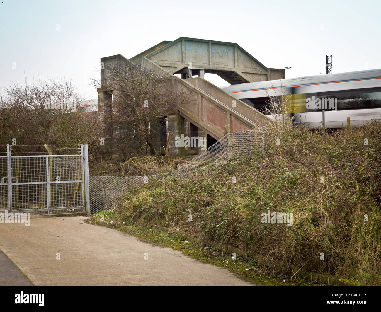 Train passing under pedestrian bridge Stock Photo - Alamy