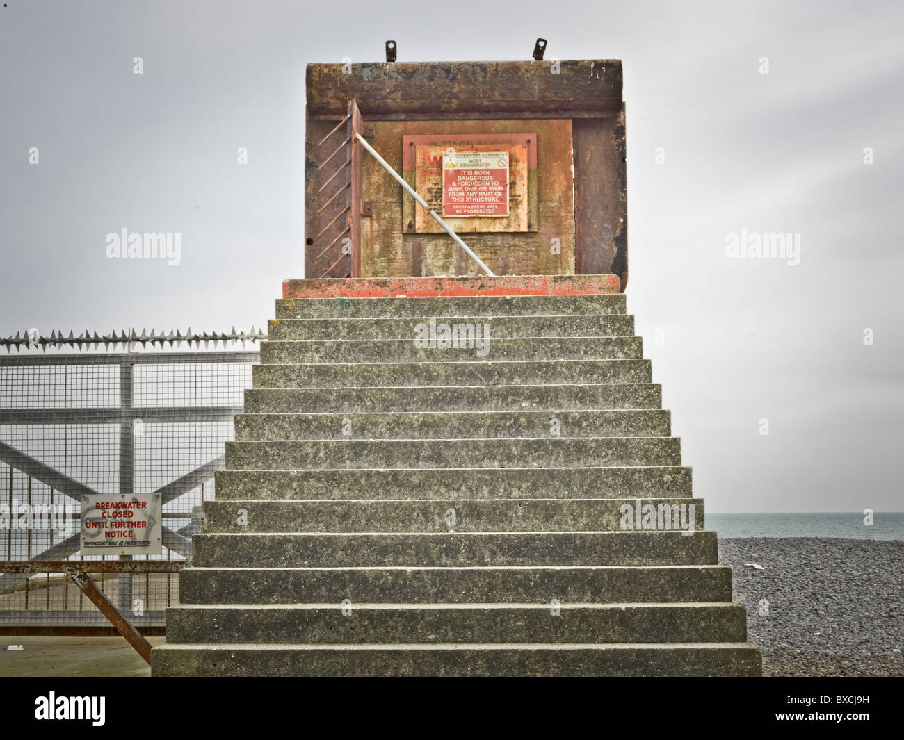 steps to closed off harbour wall on beach Stock Photo - Alamy