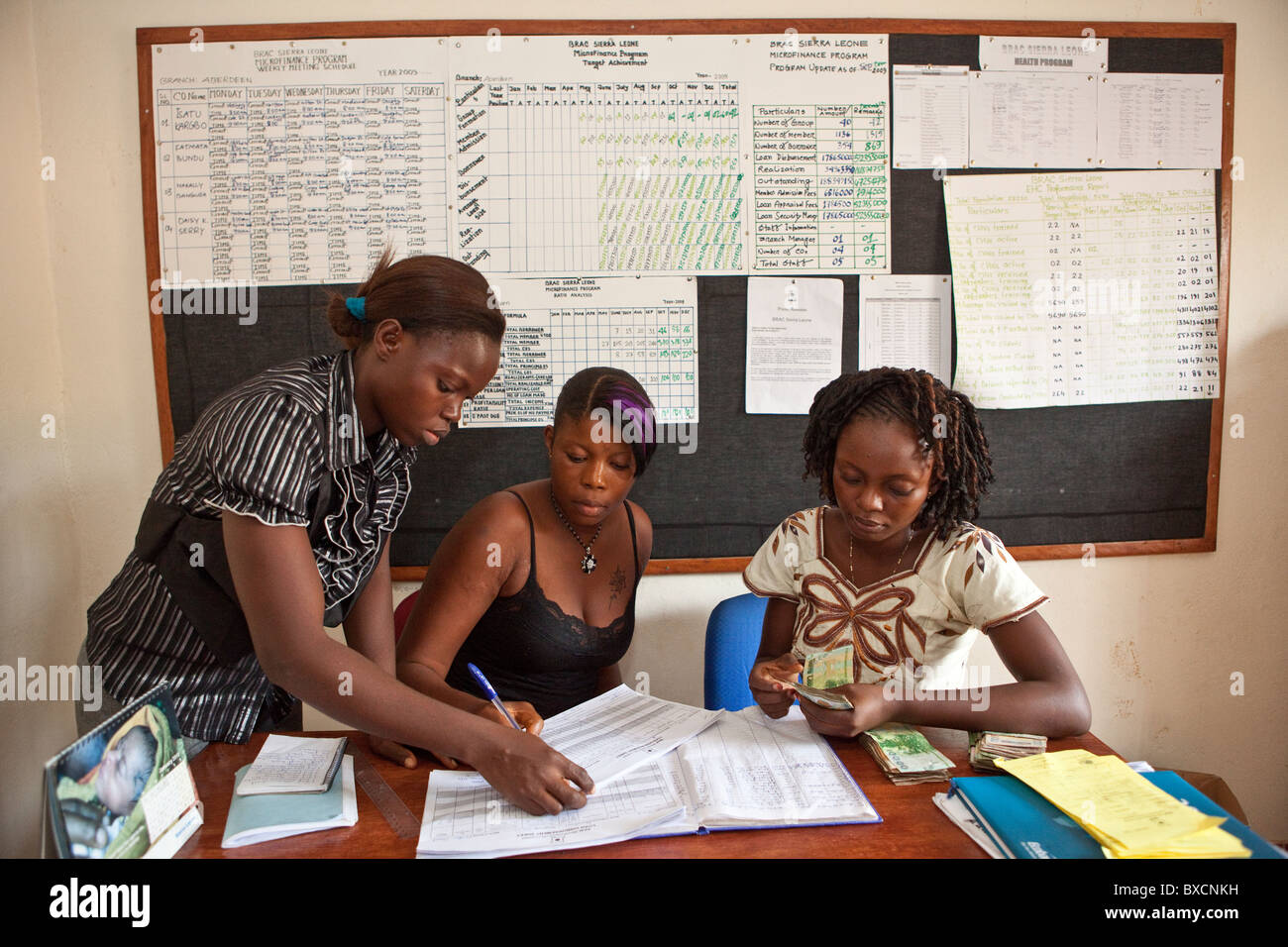 A woman signs for a microfinance loan in an office in Freetown, Sierra ...