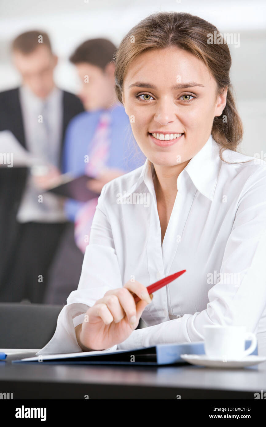Portrait of beautiful consultant sitting at the table and holding the ...