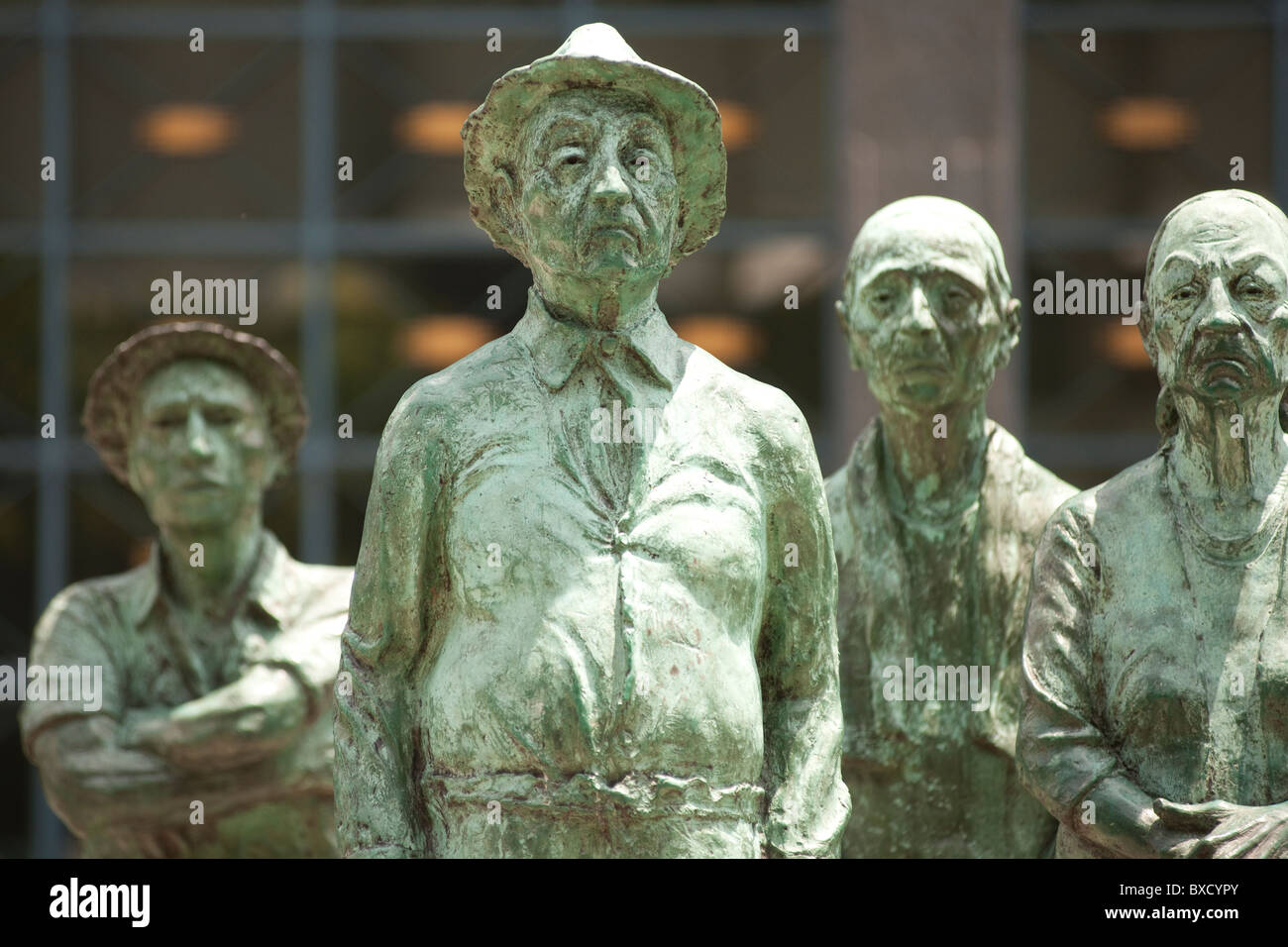 Verdigris bronze statues of agricultural workers standing in a crowd ...