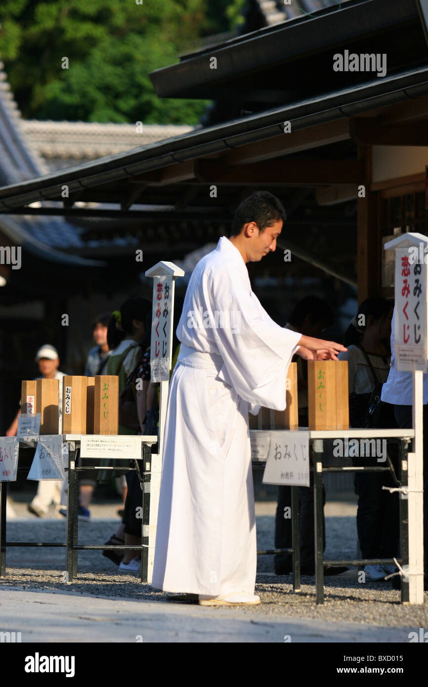 A young shinto priest arranging wooden boxes at Yasaka Shrine in Gion ...