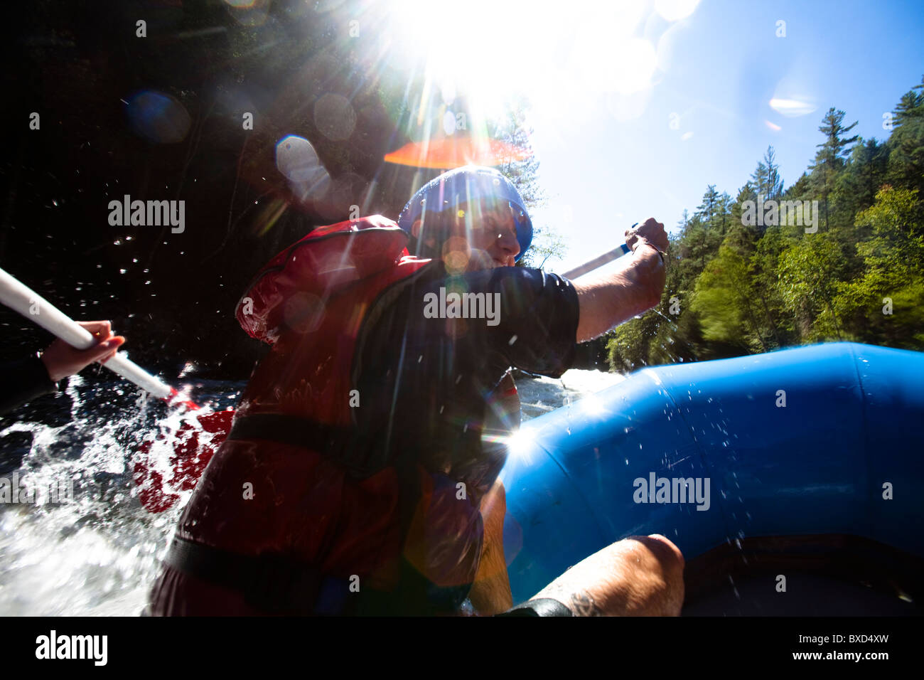 A young man paddles down a river while whitewater rafting Stock Photo ...