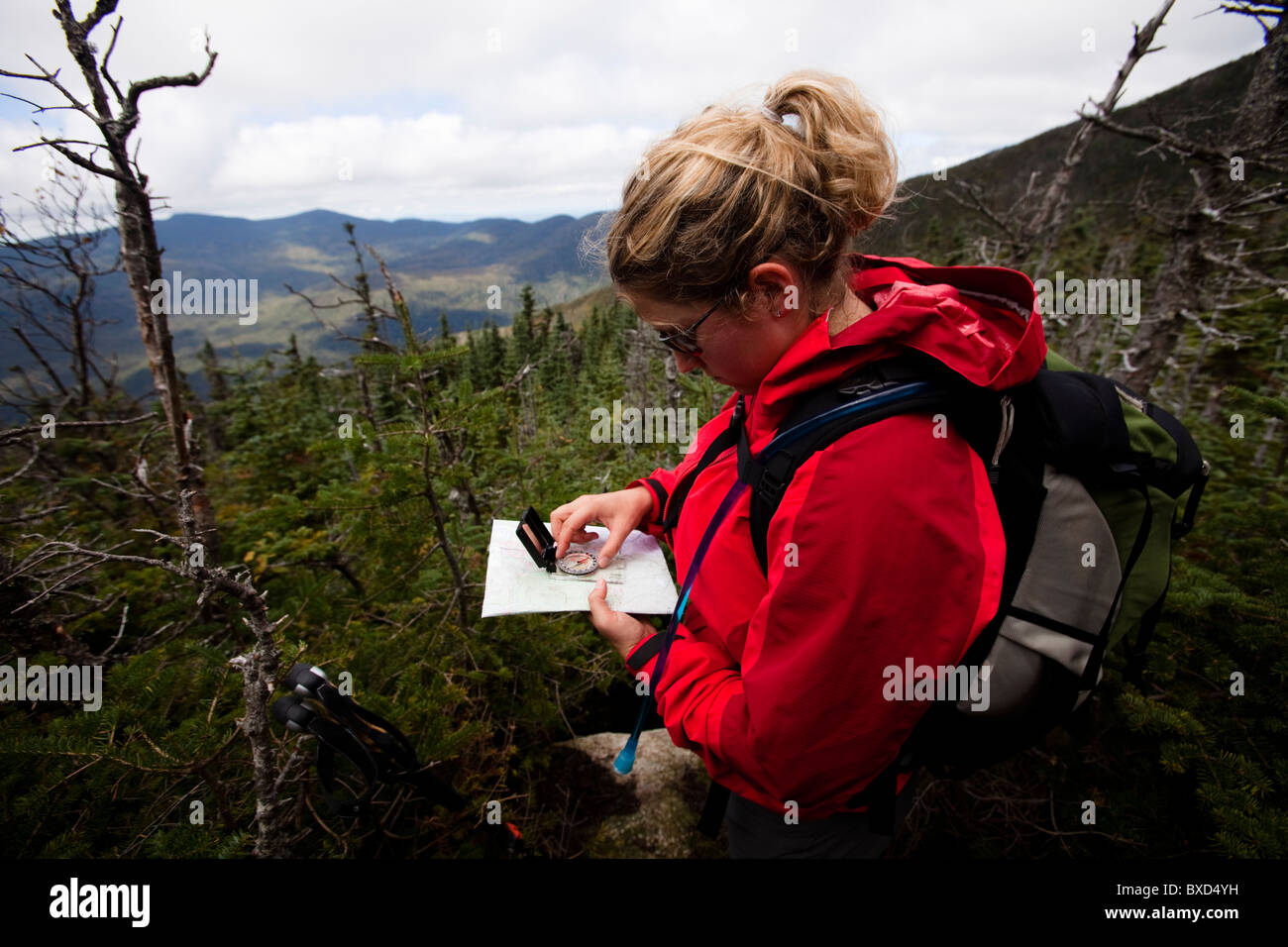 A female hiker checks her location by using a map and compass Stock ...
