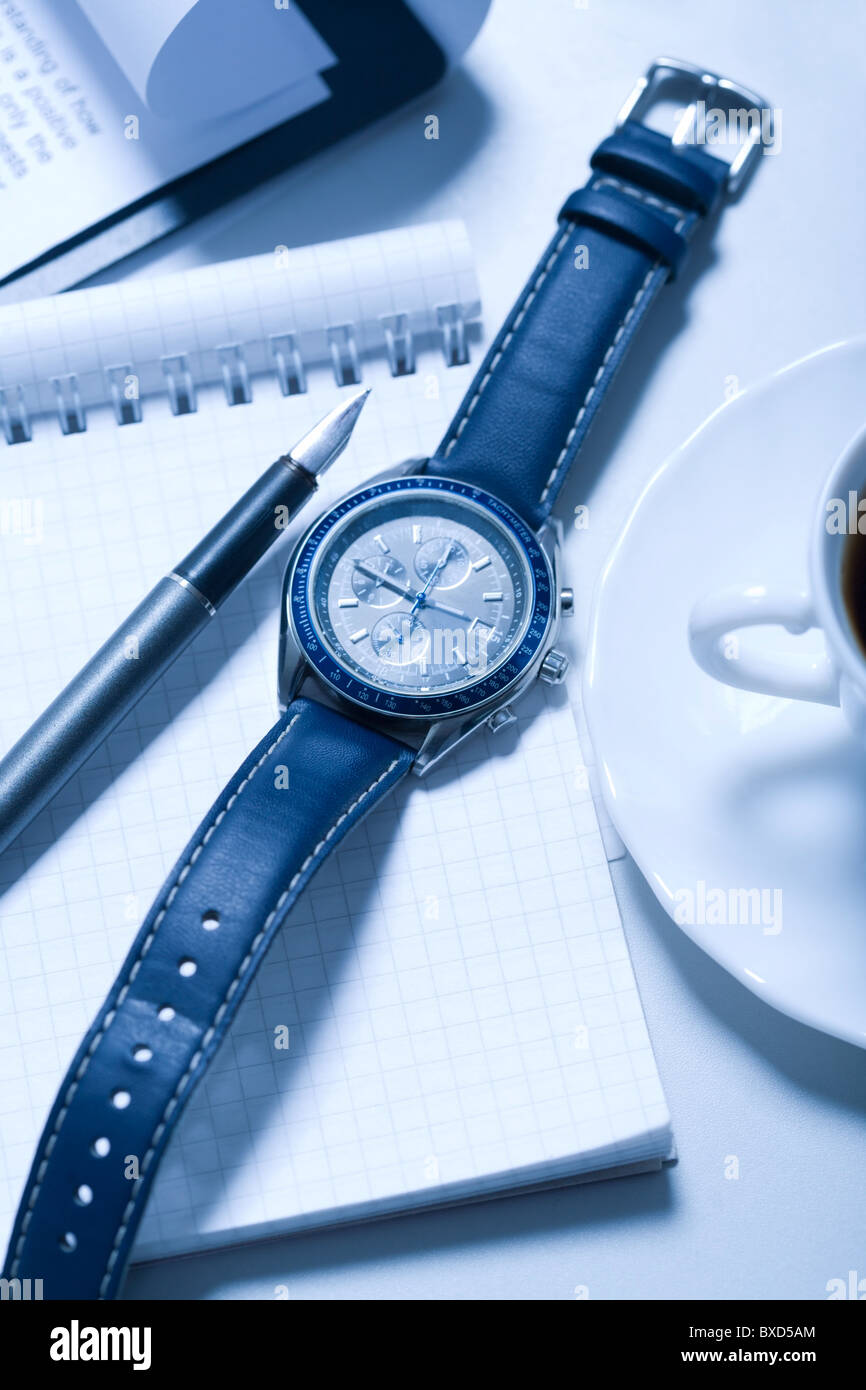 Image of working objects: wrist-watch, fountain-pen, notepad, saucer ...