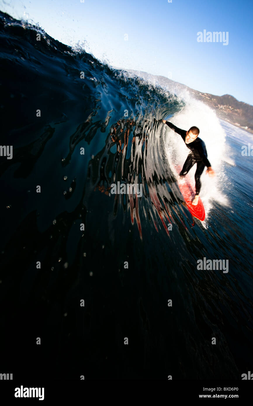 A male surfer pulls into a barrel at Zuma beach in Malibu, California ...