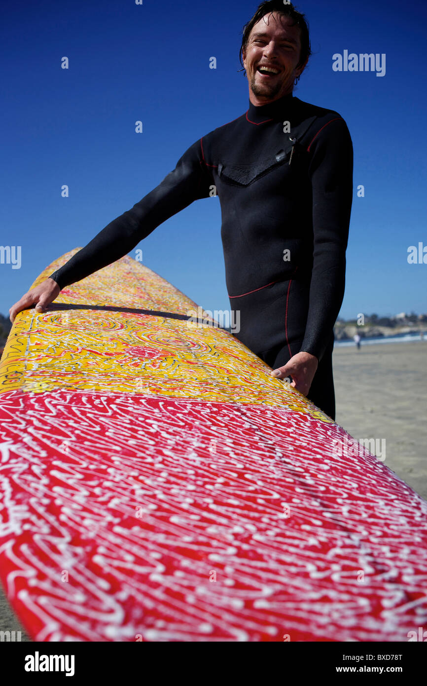 Male surfer shows his colorful surfboard Stock Photo - Alamy