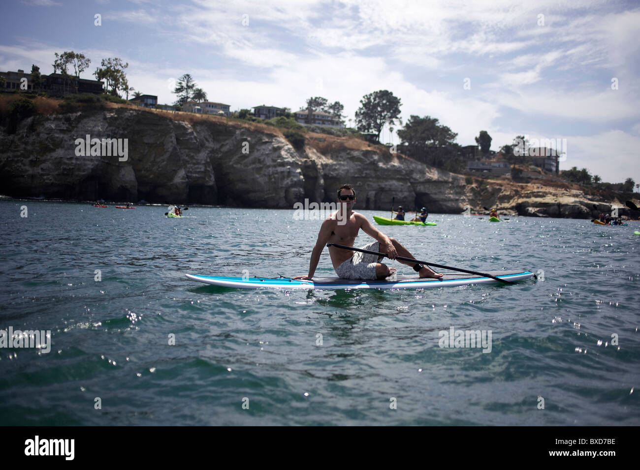 A male poses for a photo sitting on his stand up paddle board Stock ...