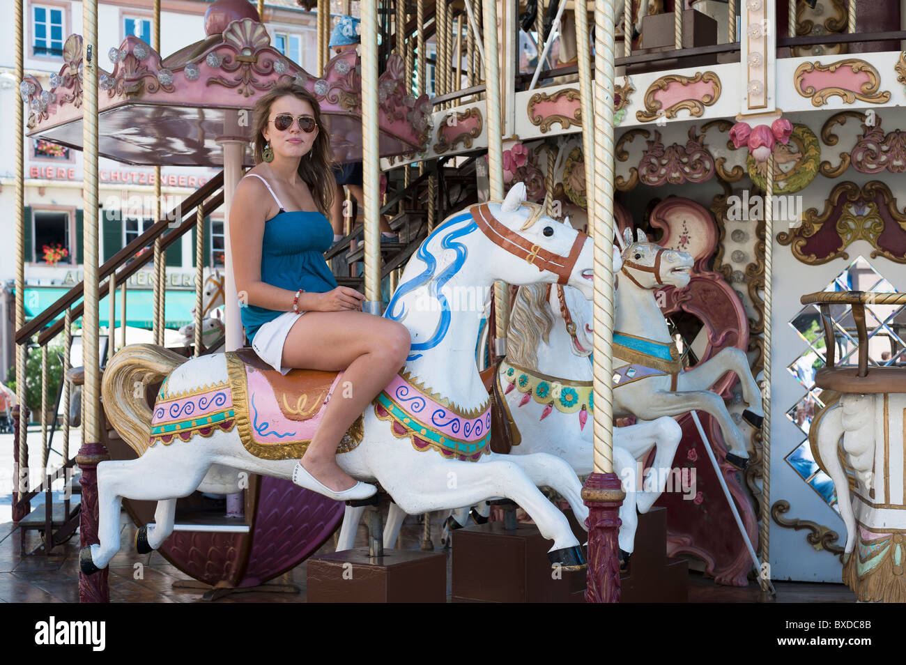 YOUNG WOMAN ON CAROUSEL'S WHITE WOODEN HORSE STRASBOURG ALSACE FRANCE ...