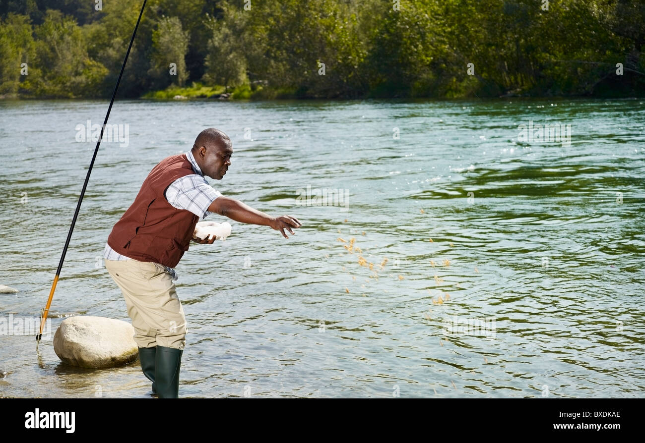 Black man throwing chum into stream Stock Photo - Alamy