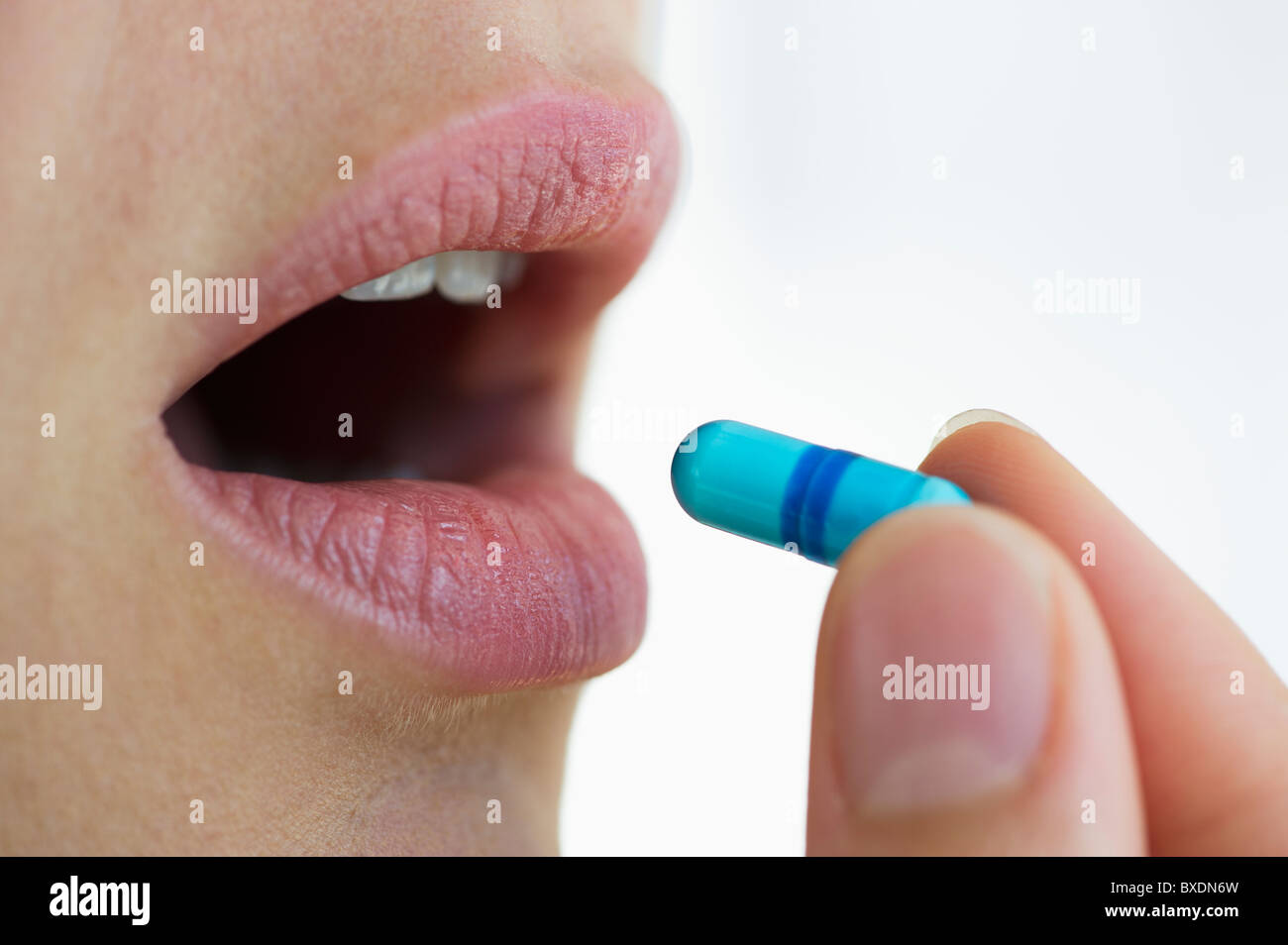 Woman putting capsule in her mouth Stock Photo - Alamy