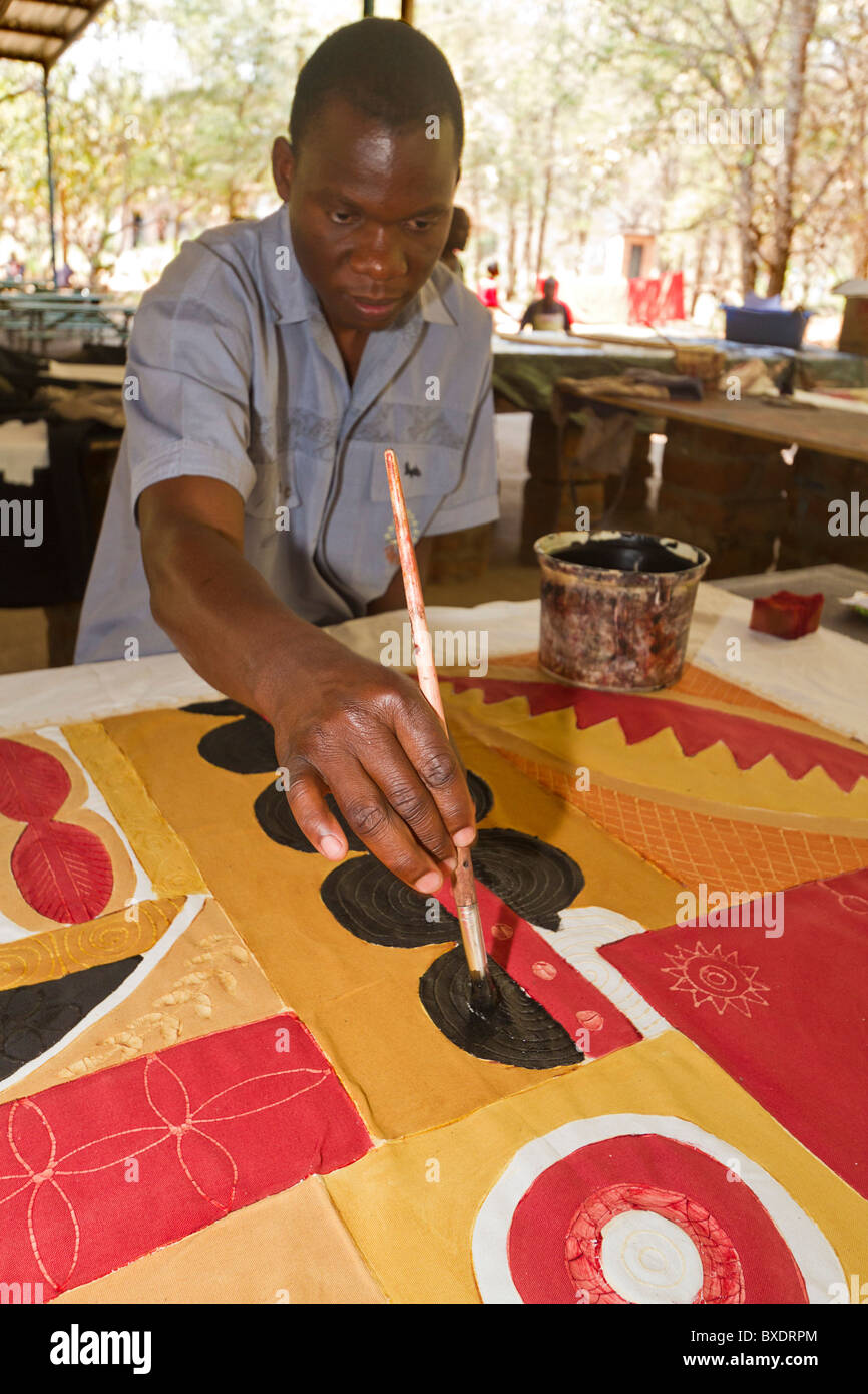 Man paints African pattern onto cloth at Tribal Textiles, a workshop in ...