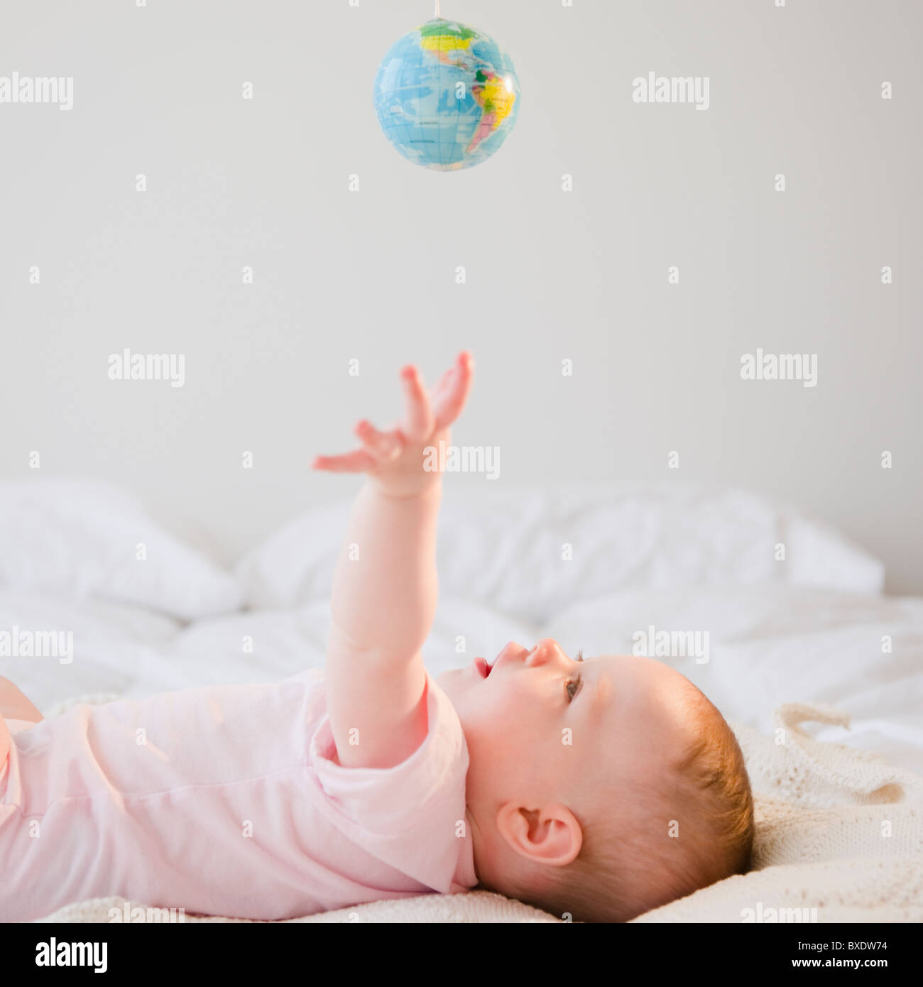 Baby reaching for globe Stock Photo - Alamy