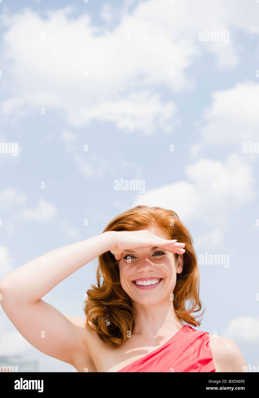 Beautiful woman shielding her eyes from the sun Stock Photo - Alamy