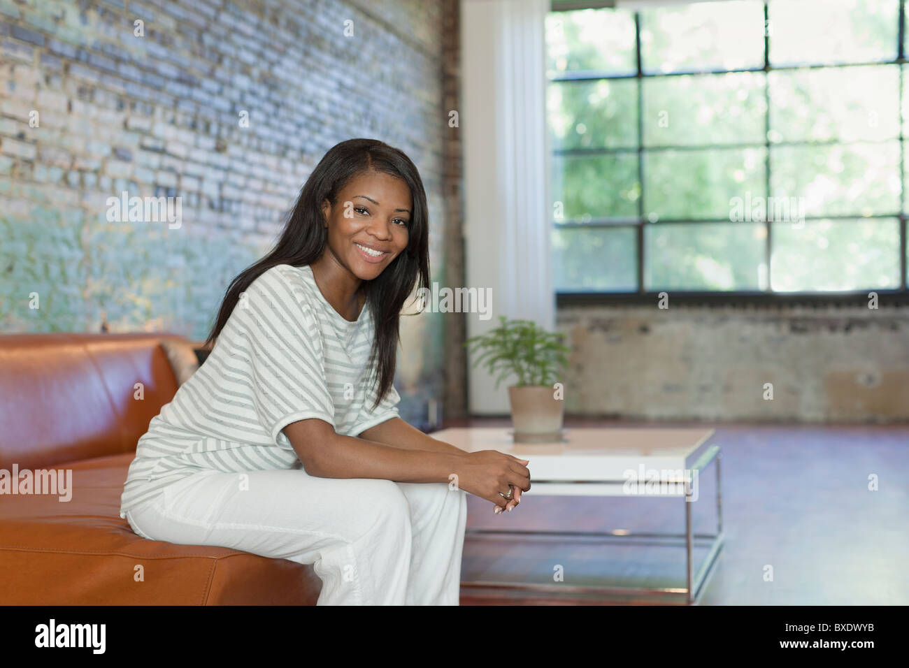 Black woman sitting on sofa in living room Stock Photo - Alamy