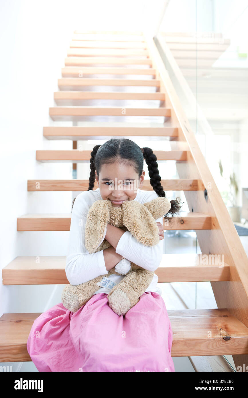 Mixed race girl sitting on steps with stuffed animal Stock Photo - Alamy