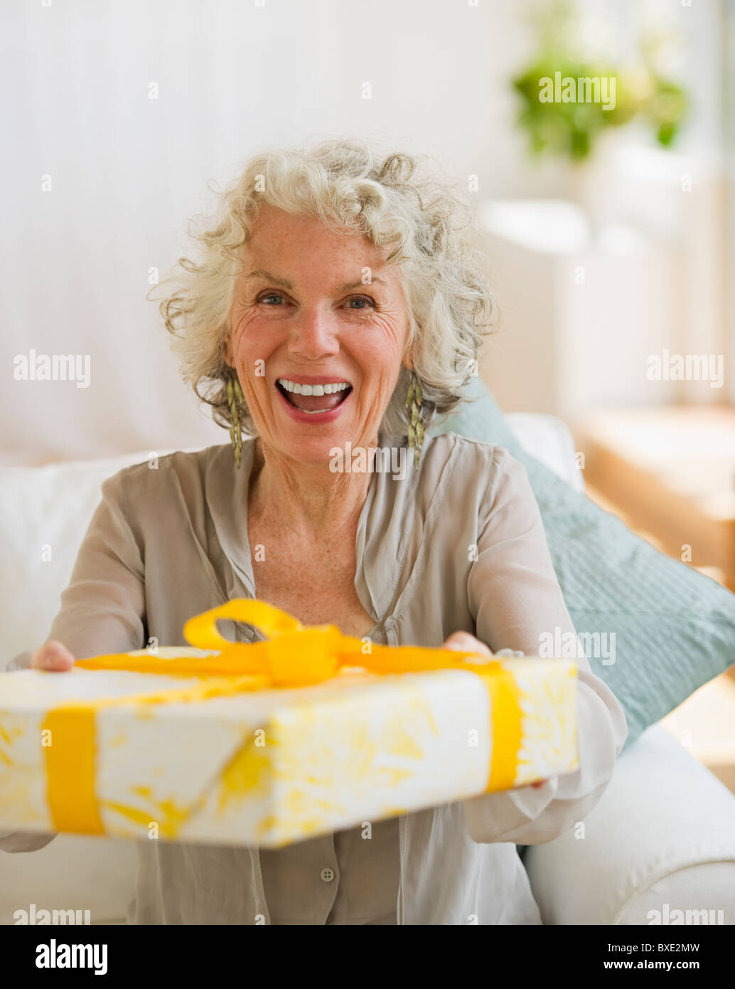 Surprised woman receiving a birthday gift Stock Photo - Alamy