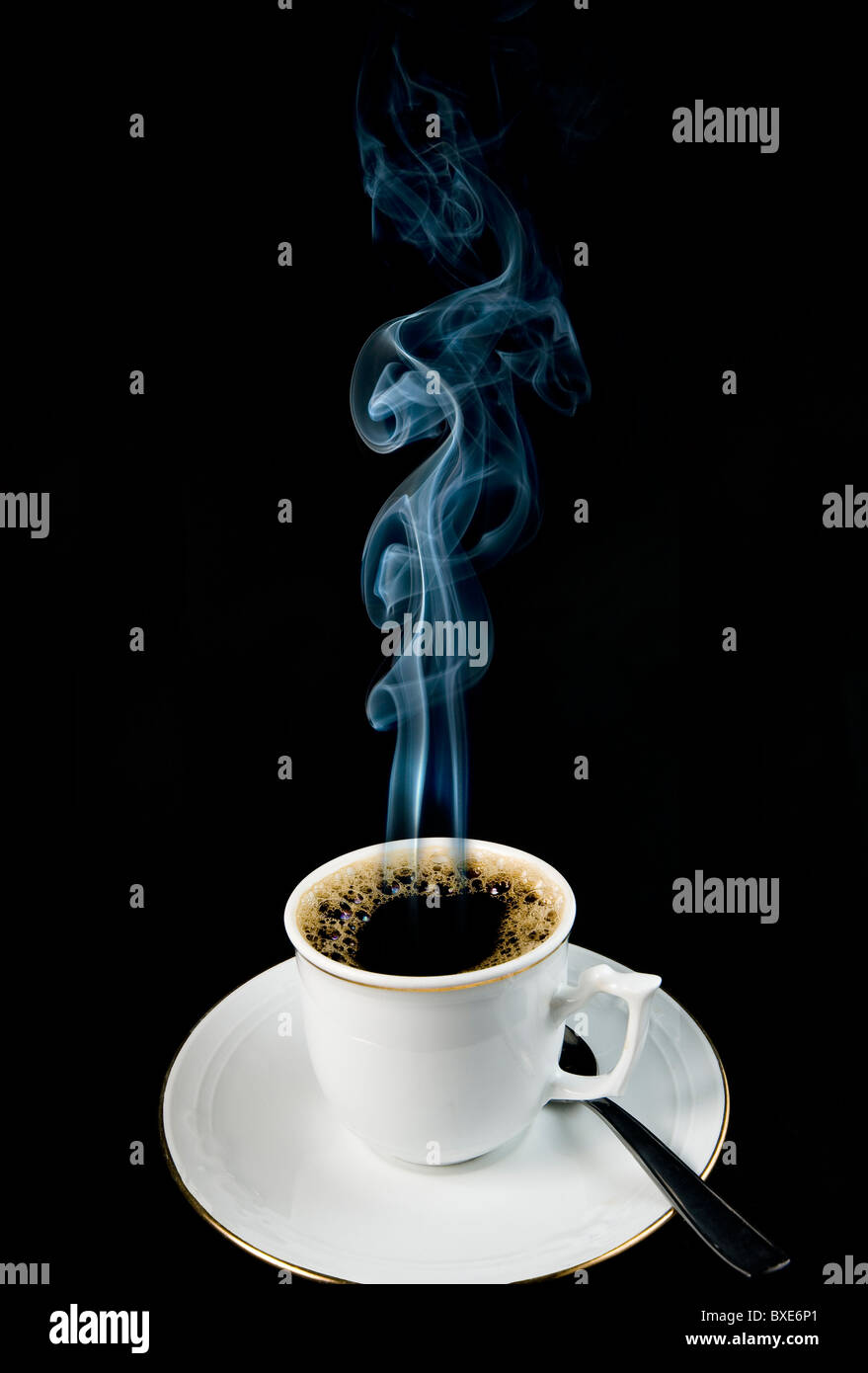 White china cup, with saucer and spoon, of steaming hot coffee. On ...
