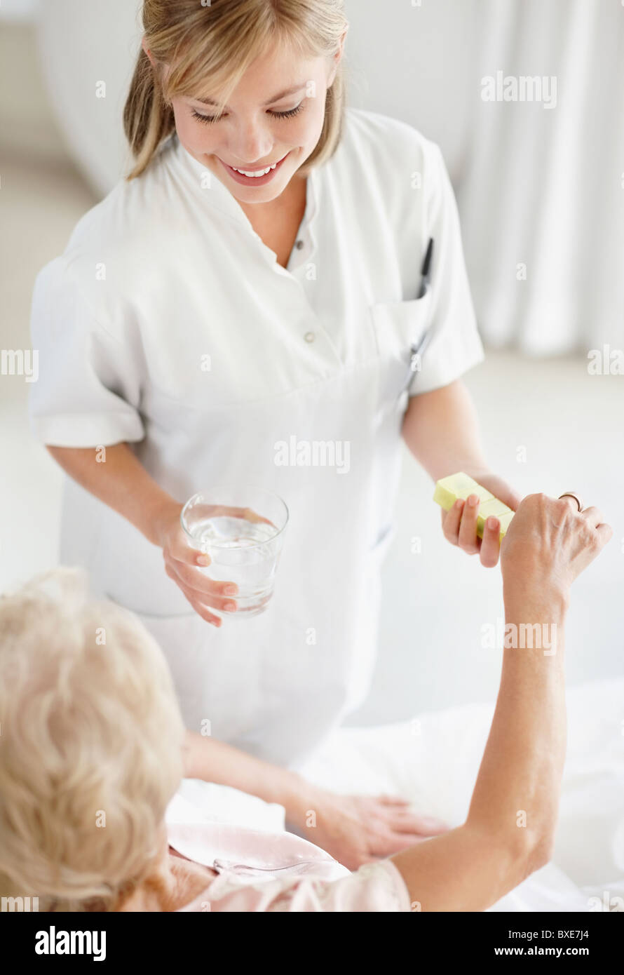 Nurse giving pill to senior woman Stock Photo - Alamy