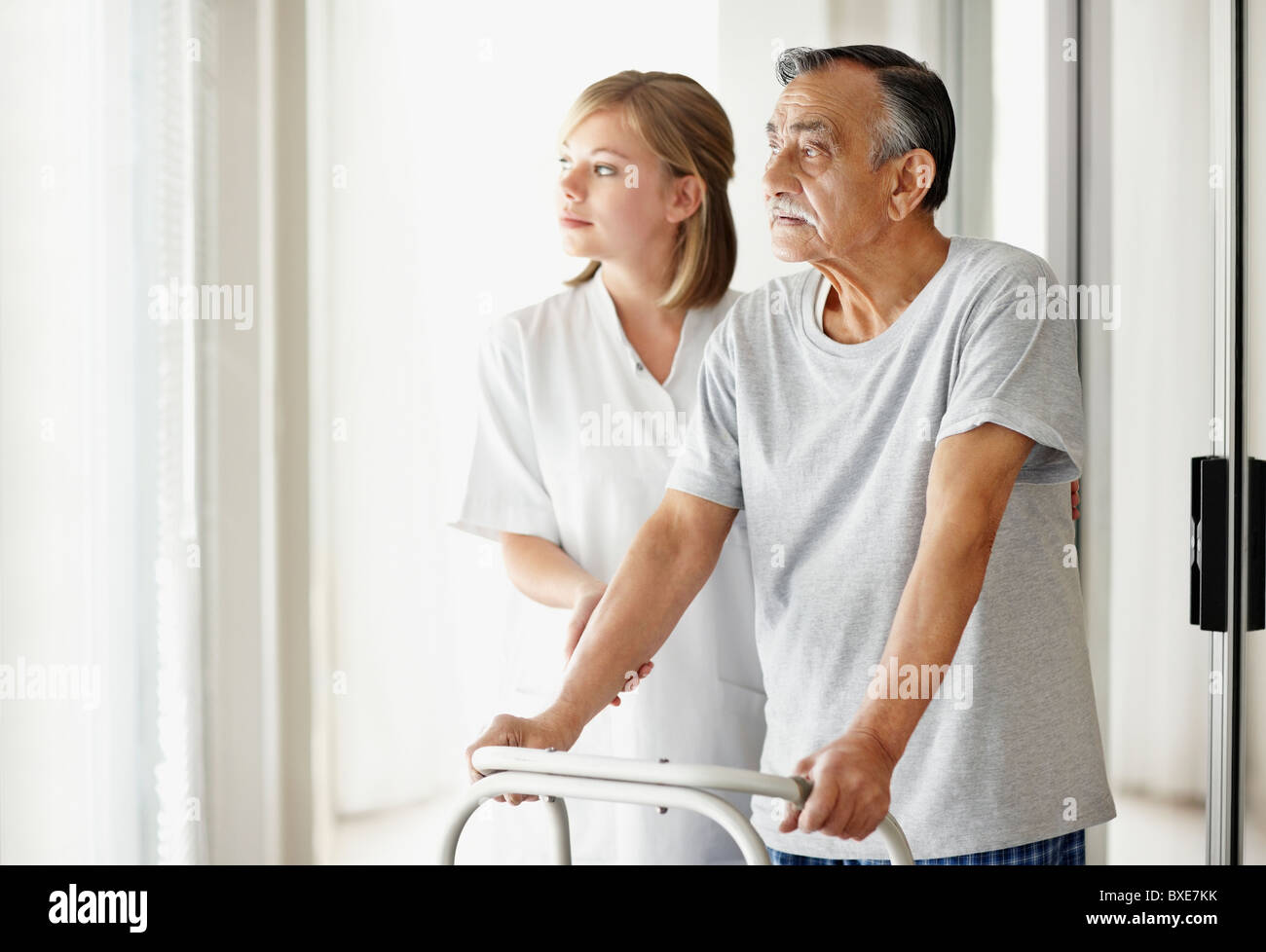 Nurse assisting patient with a walker Stock Photo - Alamy