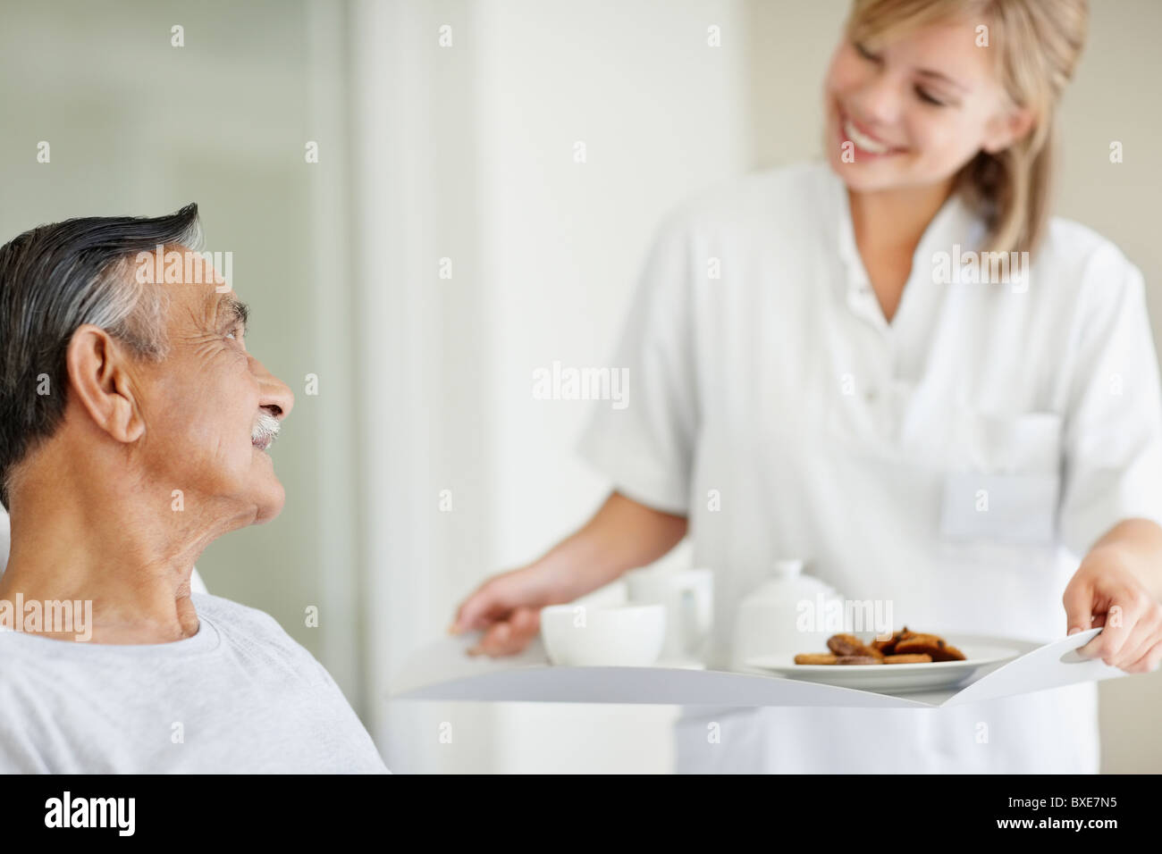 Nurse giving tray of food to patient Stock Photo - Alamy