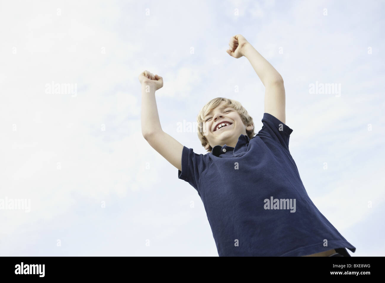 Happy young boy raising his arms in the air Stock Photo - Alamy