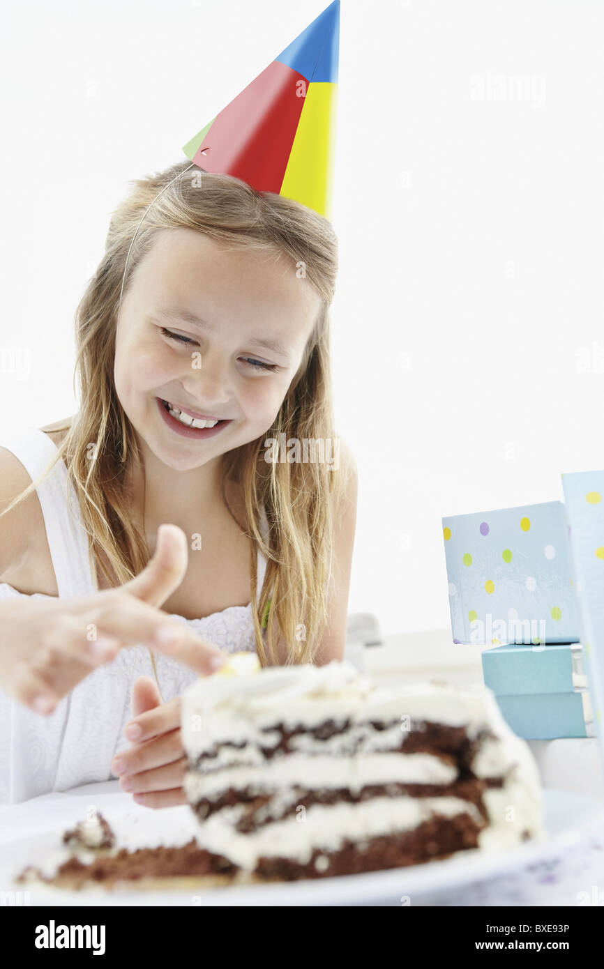 Young girl putting her finger in icing on birthday cake Stock Photo - Alamy