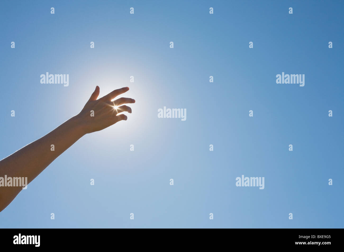 Hand in front of a sun flare in the sky Stock Photo - Alamy