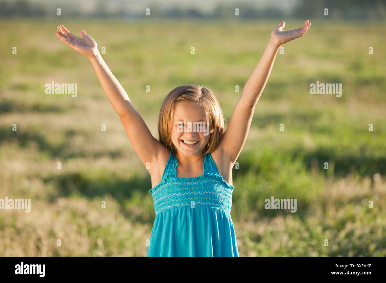 Young girl standing in field with her arms raised Stock Photo - Alamy