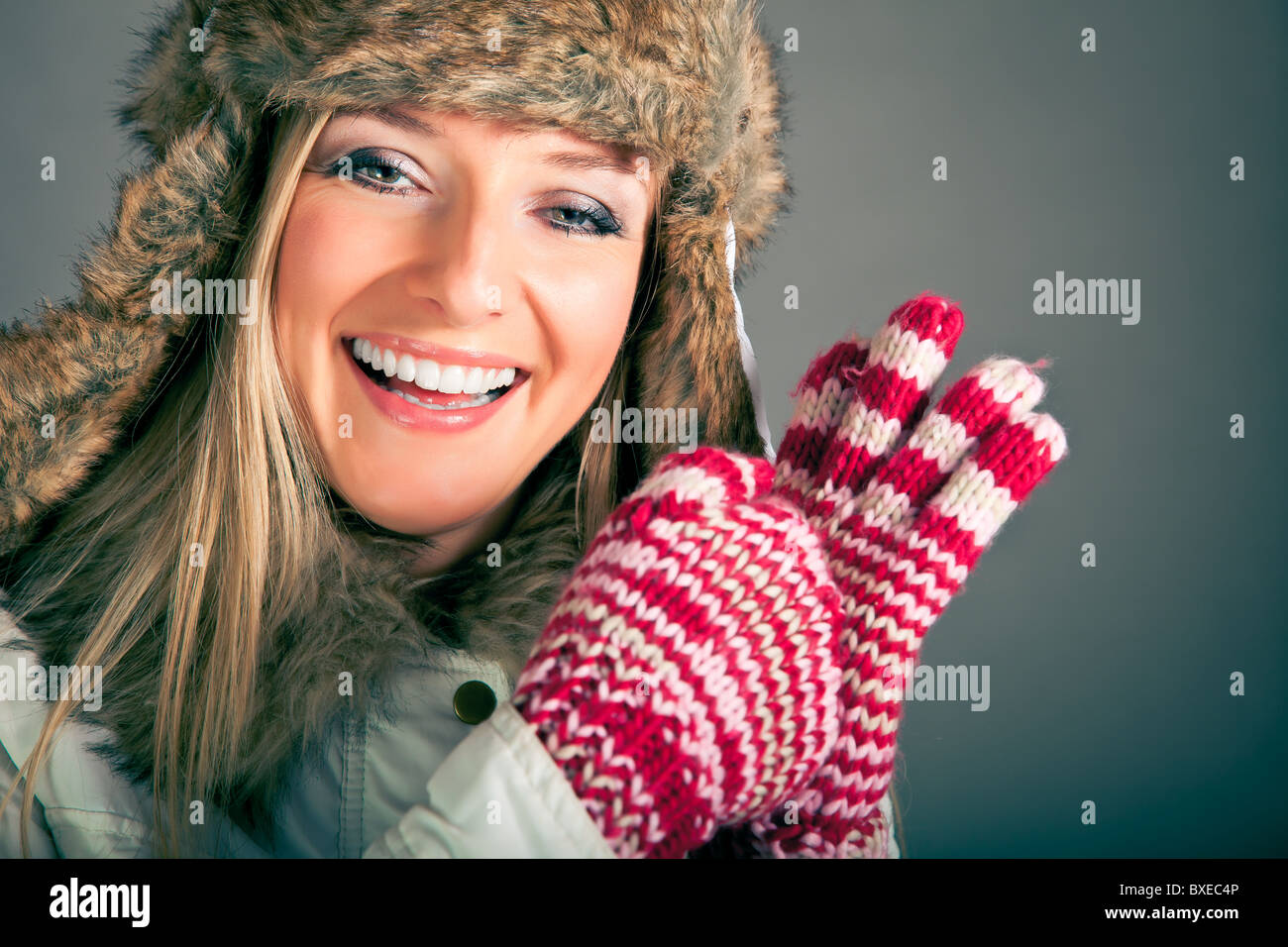 Portrait of beautiful blond woman in warm clothes on blue background ...