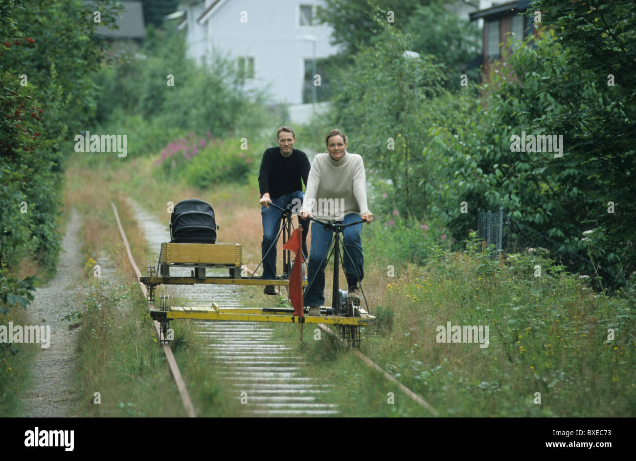 Young man, women and baby using a rail tricycle Stock Photo - Alamy