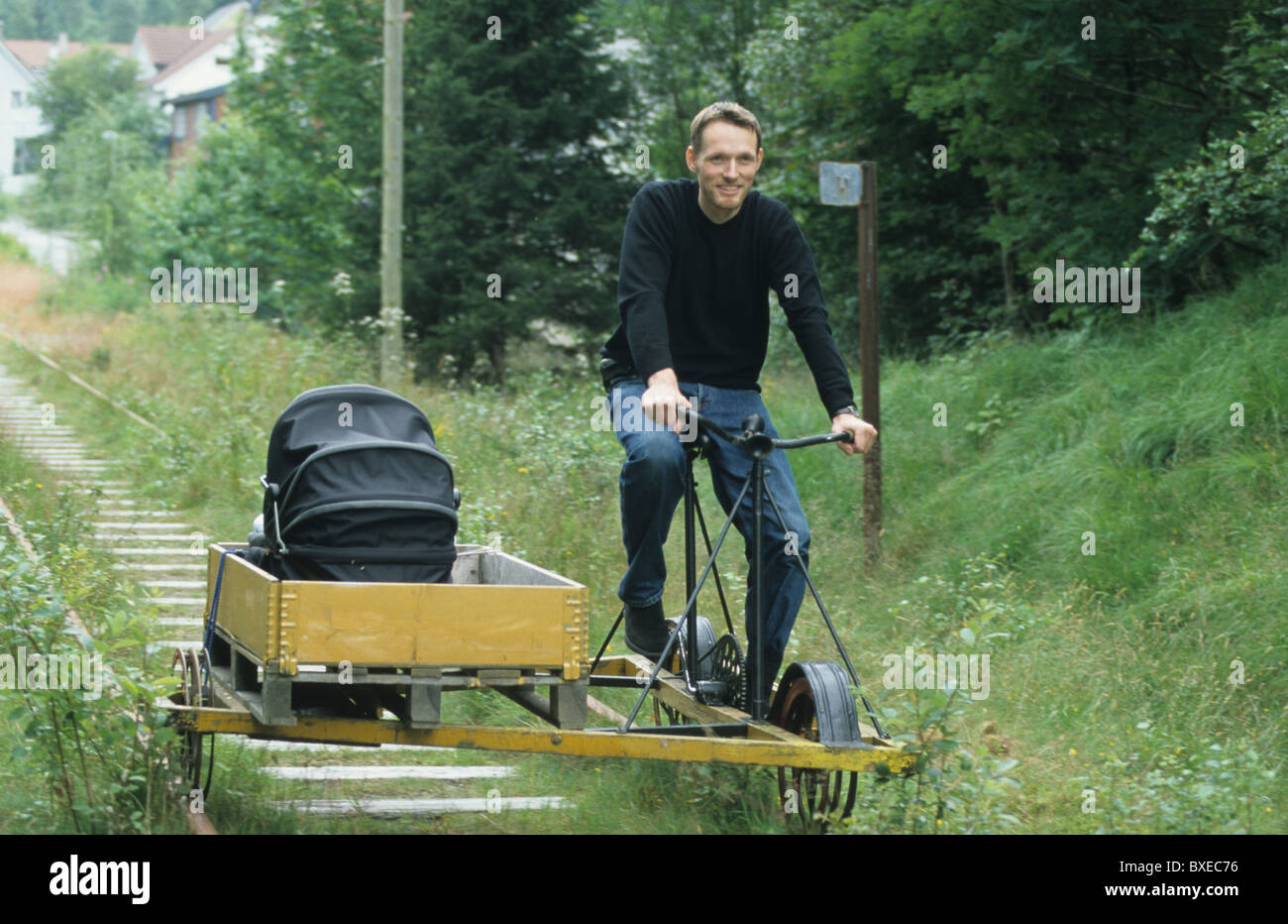 Young man, women and baby using a rail tricycle Stock Photo - Alamy