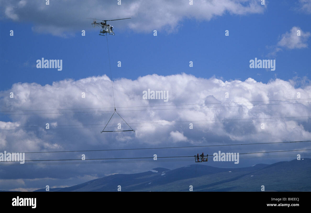 Construction workers working on energy cables high up in the air ...