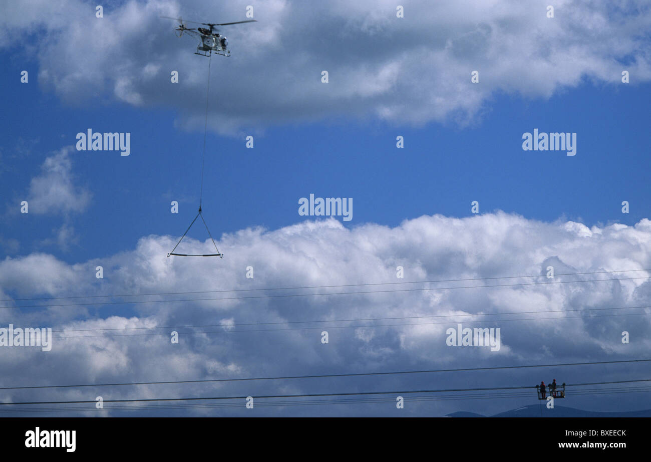 Construction workers working on energy cables high up in the air ...
