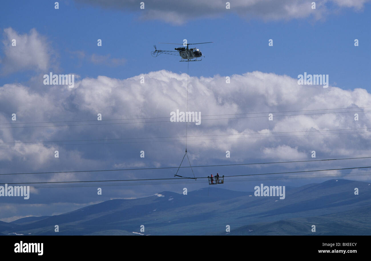 Construction workers working on energy cables high up in the air ...