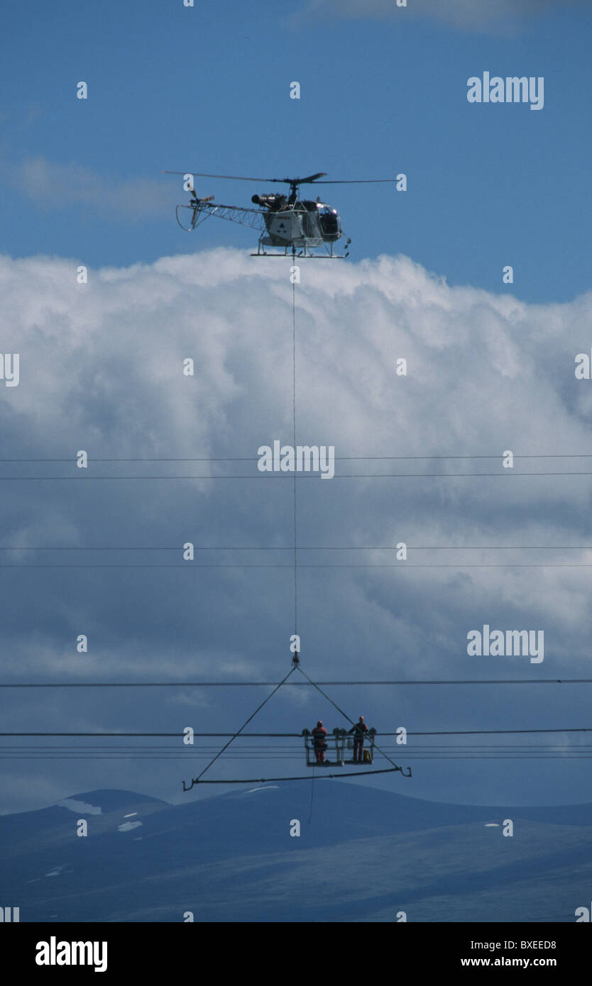 Construction workers working on energy cables high up in the air ...