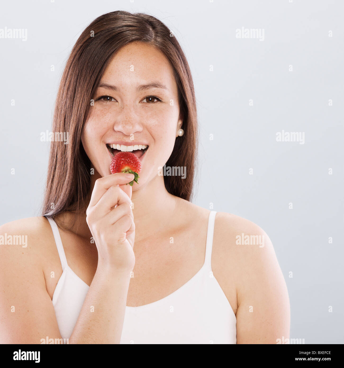 Brunette woman eating a strawberry Stock Photo - Alamy