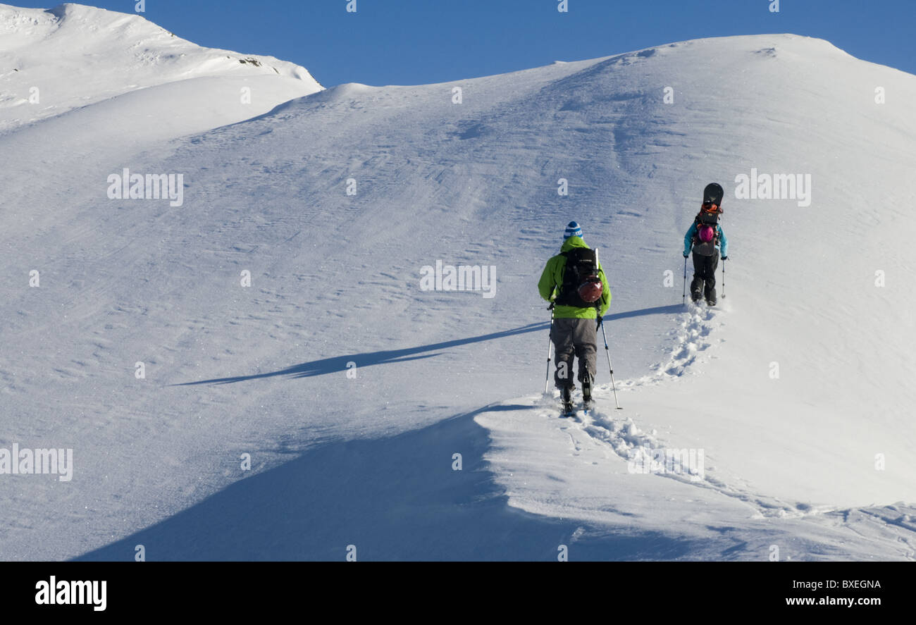 A telemark skier and a telemarker hiking up a snowy ridge near Narvik ...