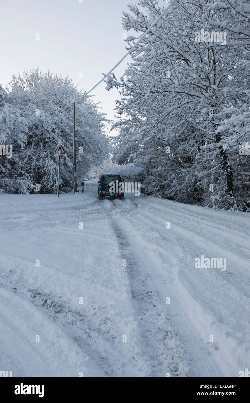 A 4x4 vehicle ploughing its way through a deep snow covered rural road ...